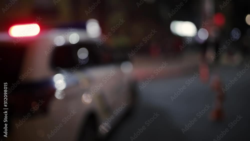 Unfocused shot of police car and traffic cones at night. Road traffic ...