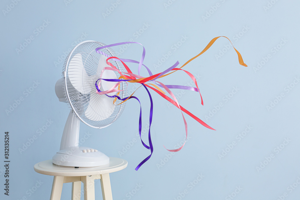Electric fan with fluttering ribbons on color background Stock Photo ...
