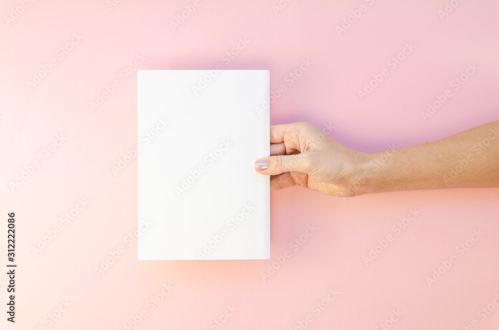Women hand hold white template paper or magazine on pink background ...