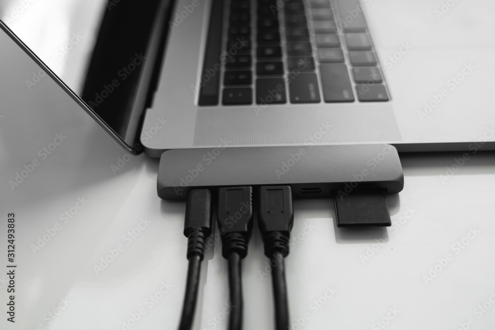 Laptop with USB Type-C adapter with pluged USB cables and SD card. The ...