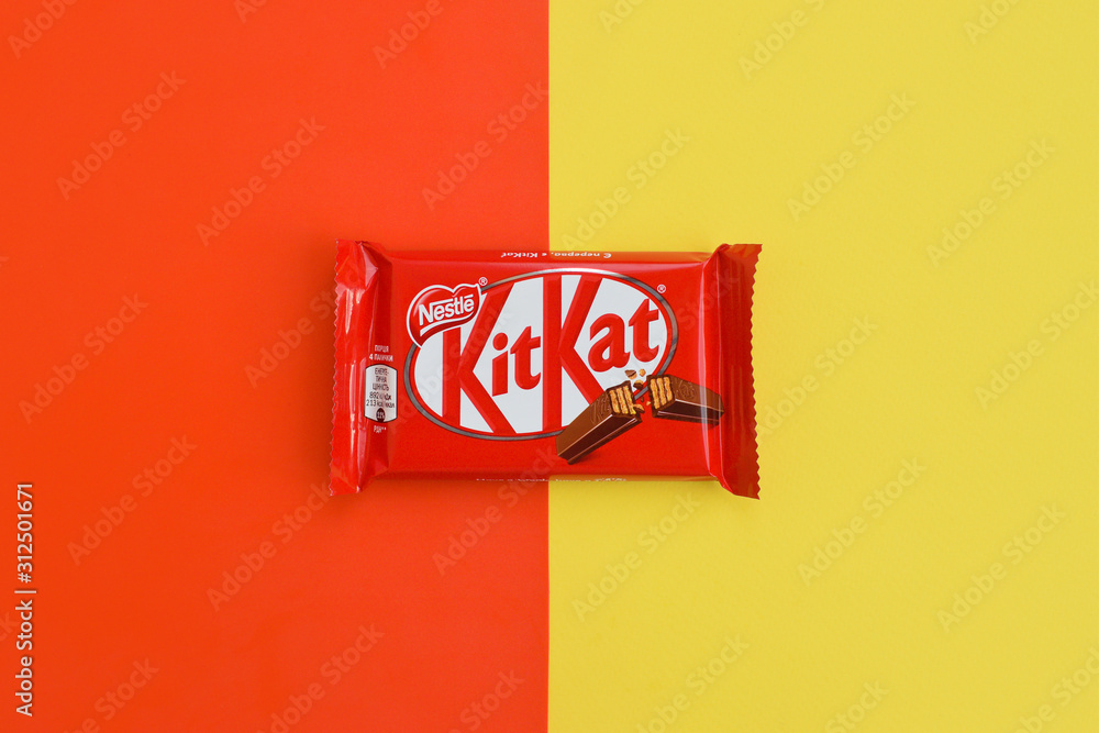 Kit Kat chocolate bars in red wrapping lies on yellow and red ...