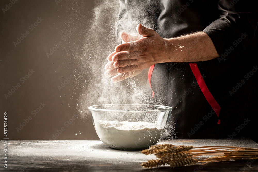 chef in black uniform sprinkles white wheat flour in different ...