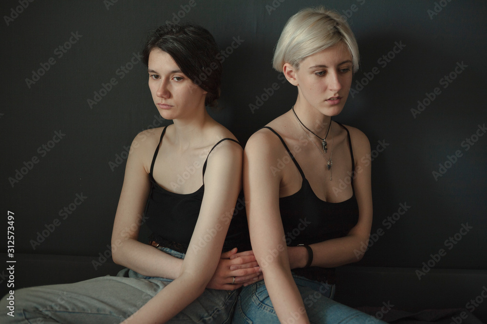 two girls in identical clothes holding their hands on a neutral ...