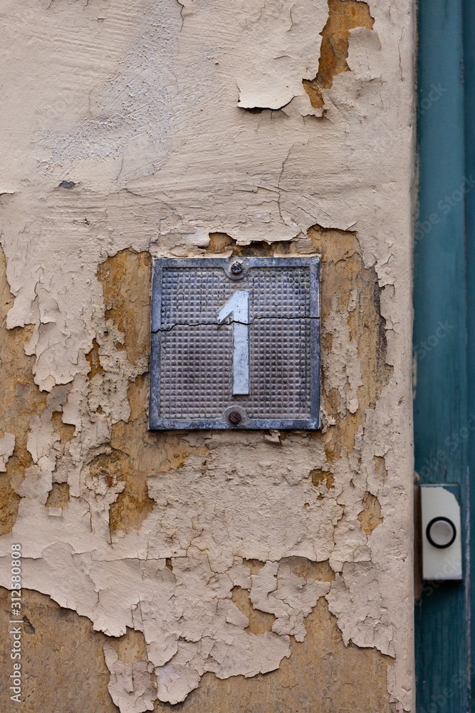 number 1 old cracking house number sign on beige wall with peeling ...
