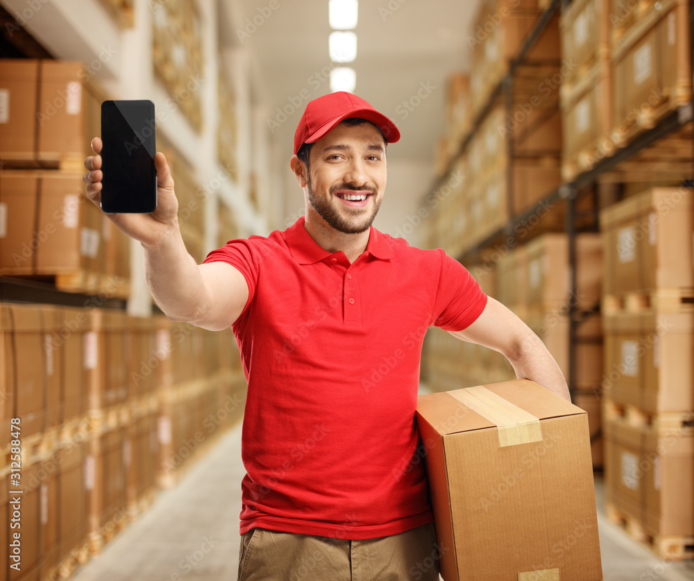 Delivery guy with a package showing a mobile phone in a warehouse Stock ...