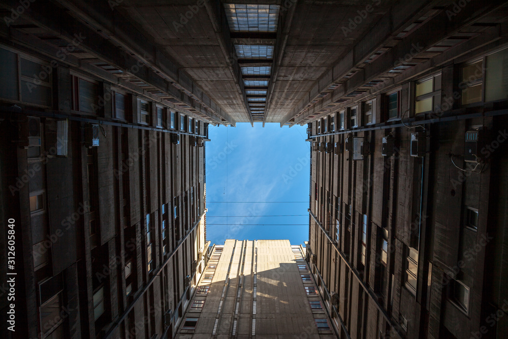 Sunlight and blue sky seen from a square inner courtyard of a high rise ...