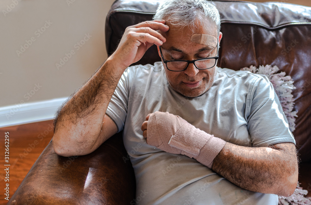 Older man sitting with head injury and sprained wrist, telehealth Stock ...