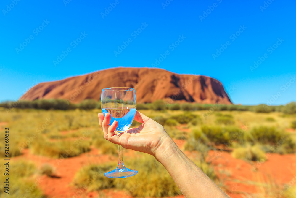 Foto de Woman's hand holding a glass goblet that reflecting Ayers Rock ...