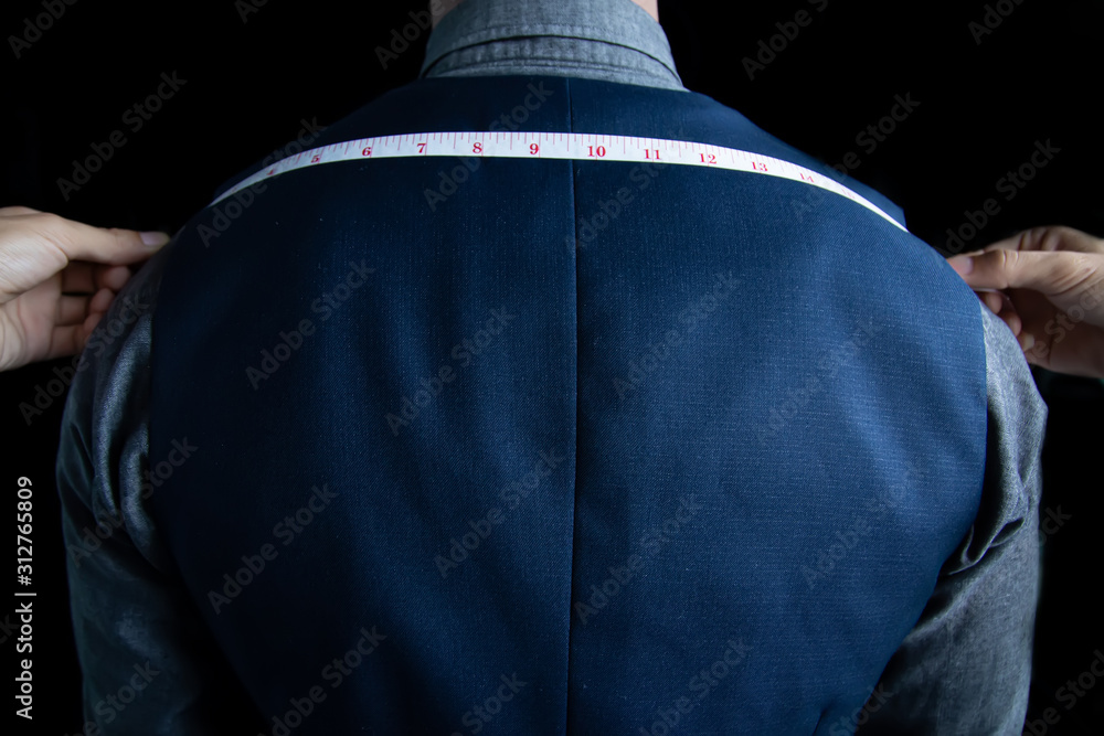The dressmaker was measuring the width of the back of the man wearing a ...