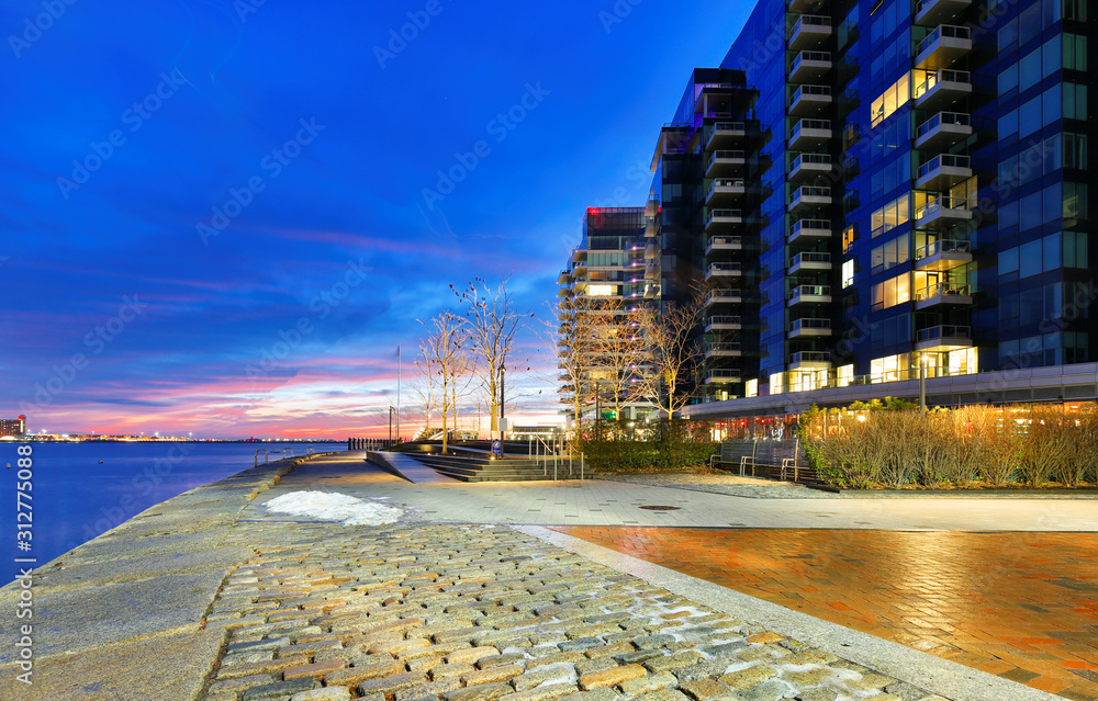 Boston Harbor before sunrise. Photo shows Fan Pier Park brick sidewalk ...