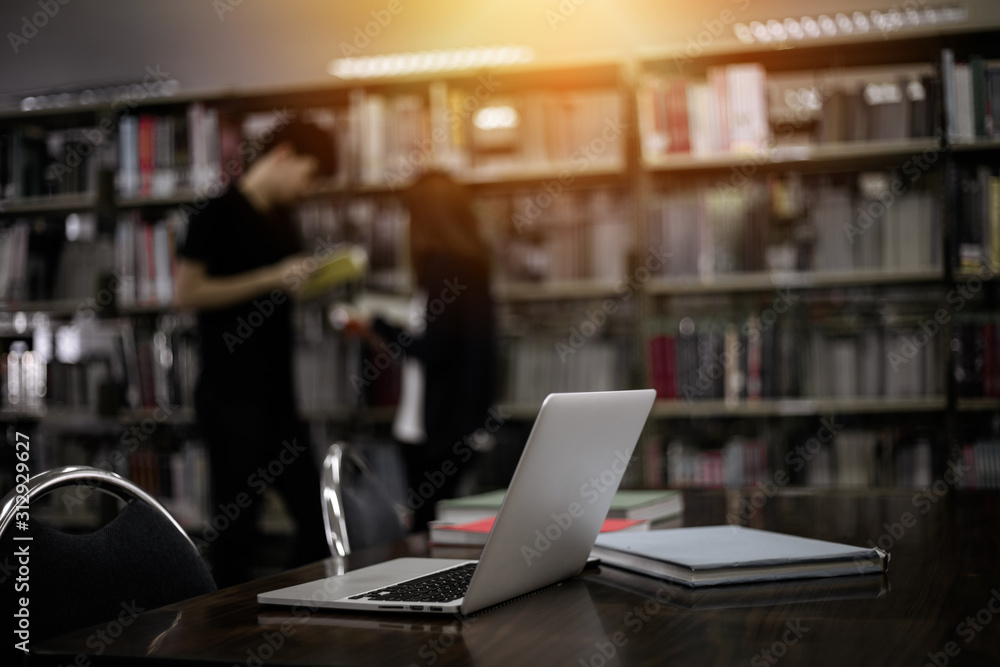Tablet and old book in library with open textbook, stack piles of literature text archive on ...