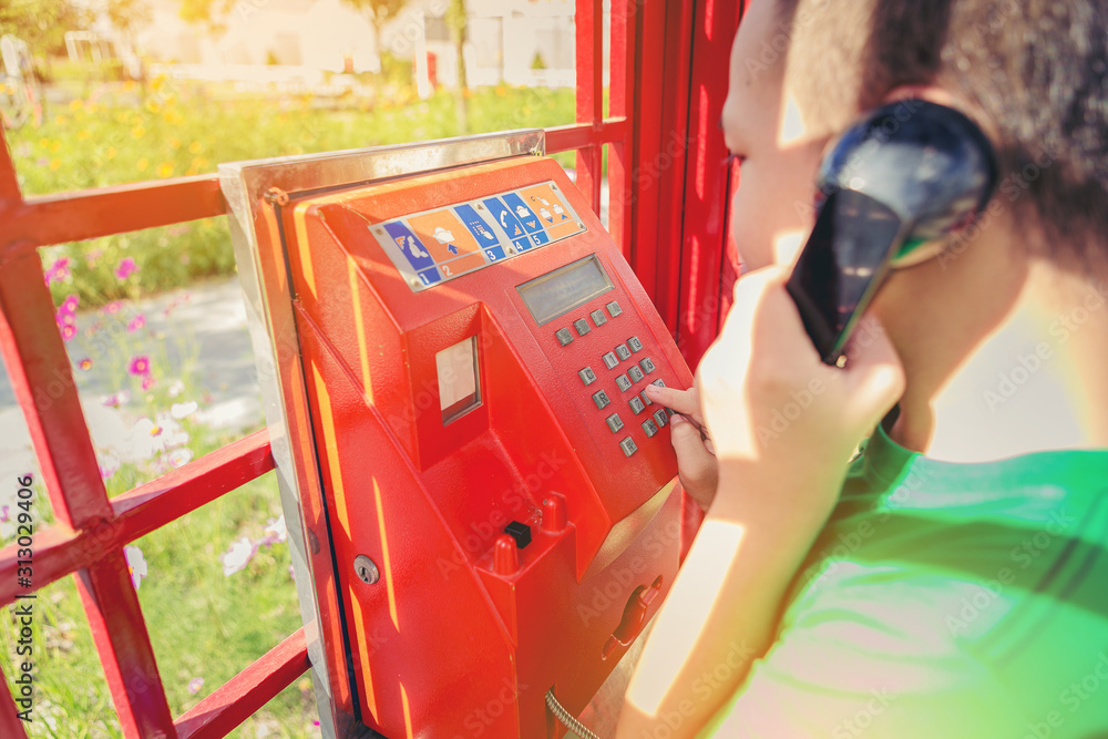 Boy stands in a red telephone booth and pushing number the old ...