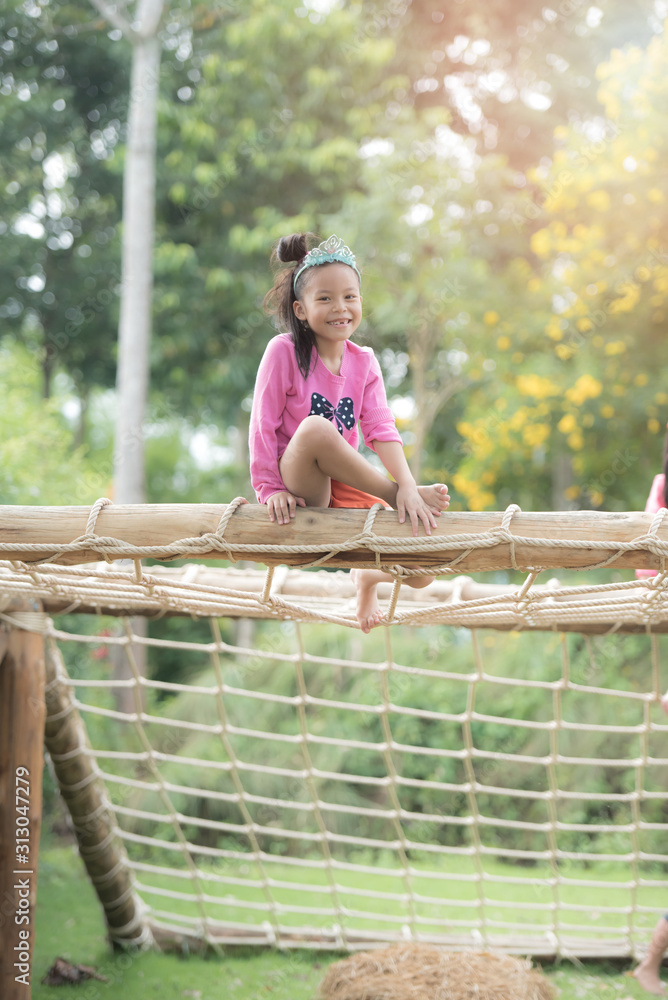 Little Girl with climbing gear climbing rope trail in an adventure park ...