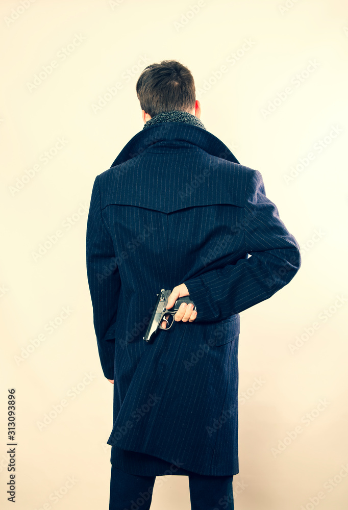 A man holding a gun on his back. The gunman held his gun behind him ...