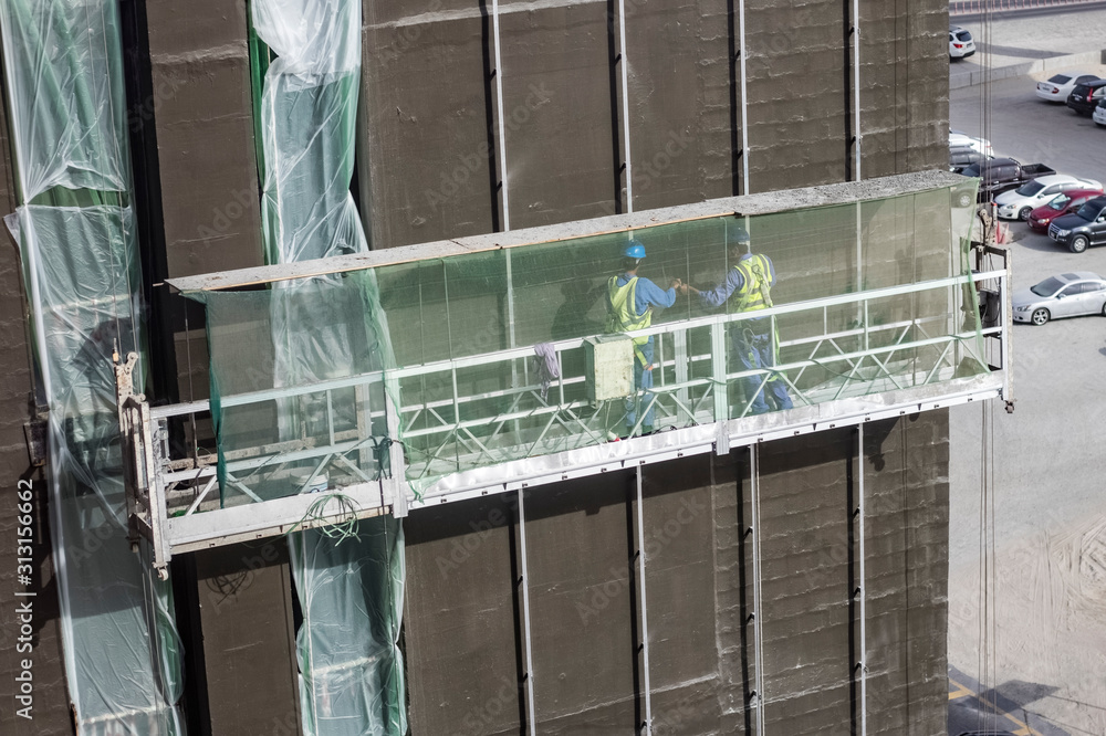 facade cladding of the building by the builders on an overhead crane ...