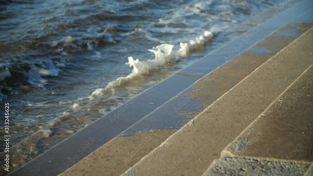 4K shot of ocean waves crashing onto the promenade stairs on a hot ...