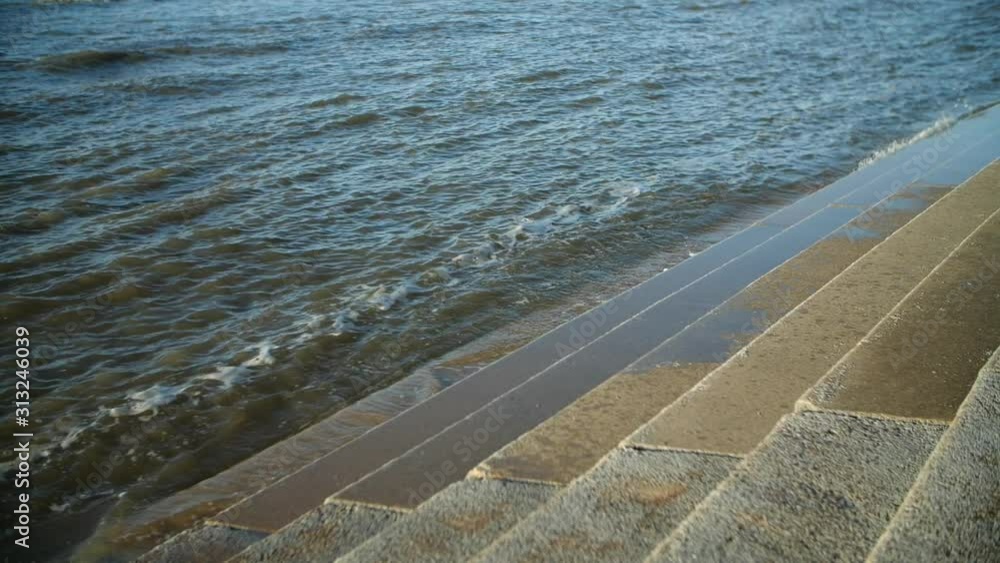 Slow motion shot of ocean waves crashing onto the promenade stairs on a ...