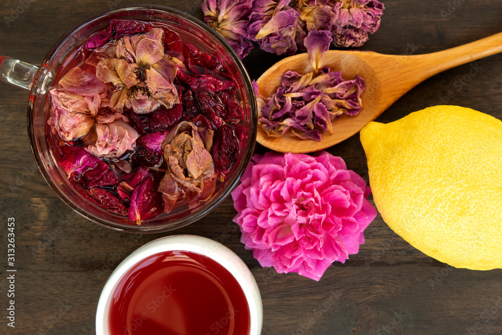 dried pink roses and tea in glass on black wood background, dry rose ...