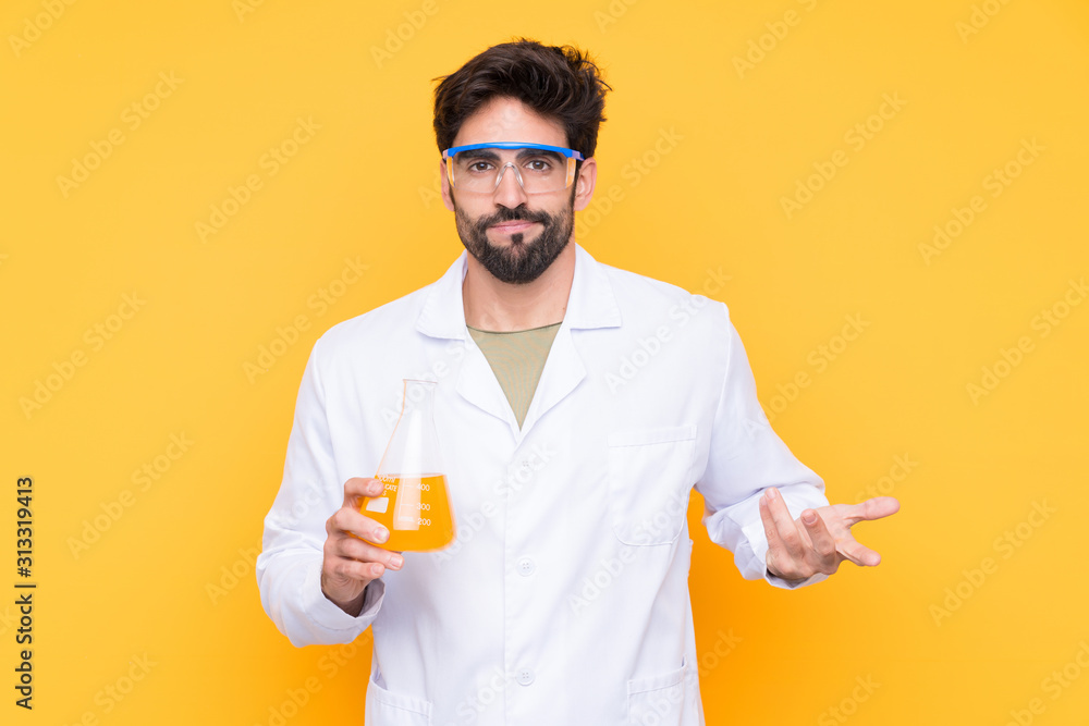 Young scientific man over isolated yellow background making doubts ...