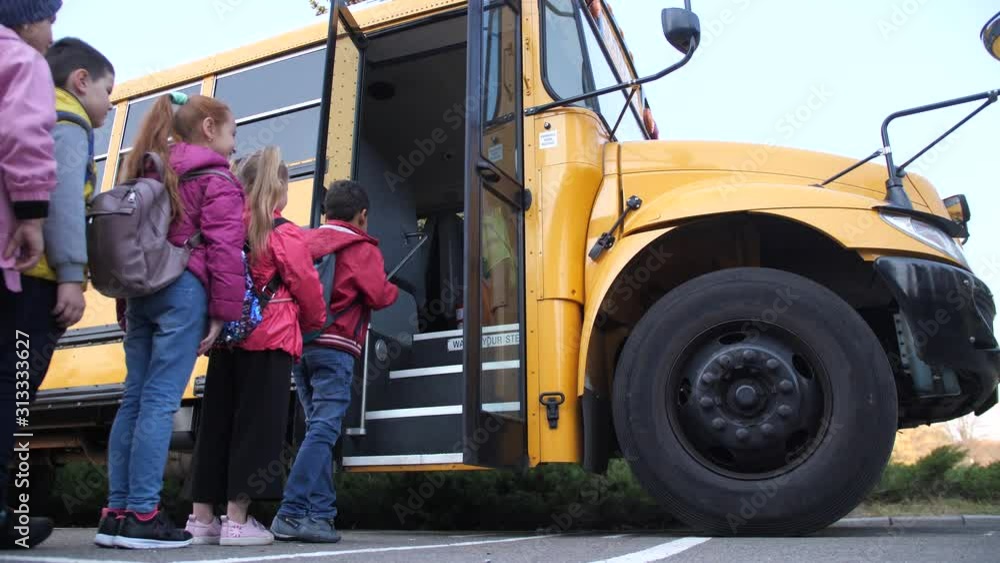 Lined up little pupils getting on yellow school bus to go home after ...