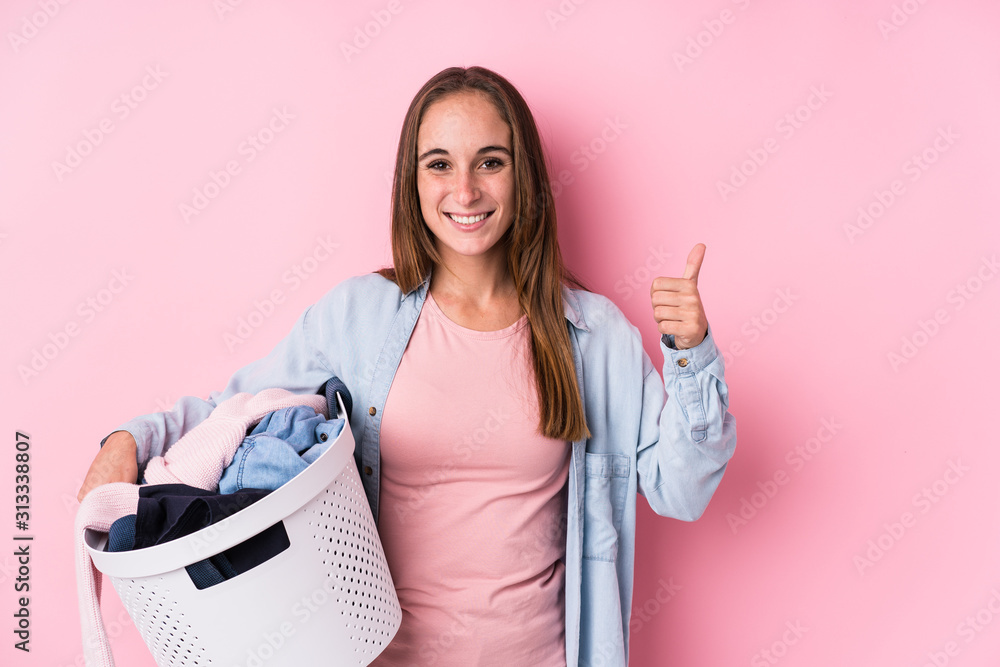 Young caucasian woman picking up dirty clothes isolated smiling and ...