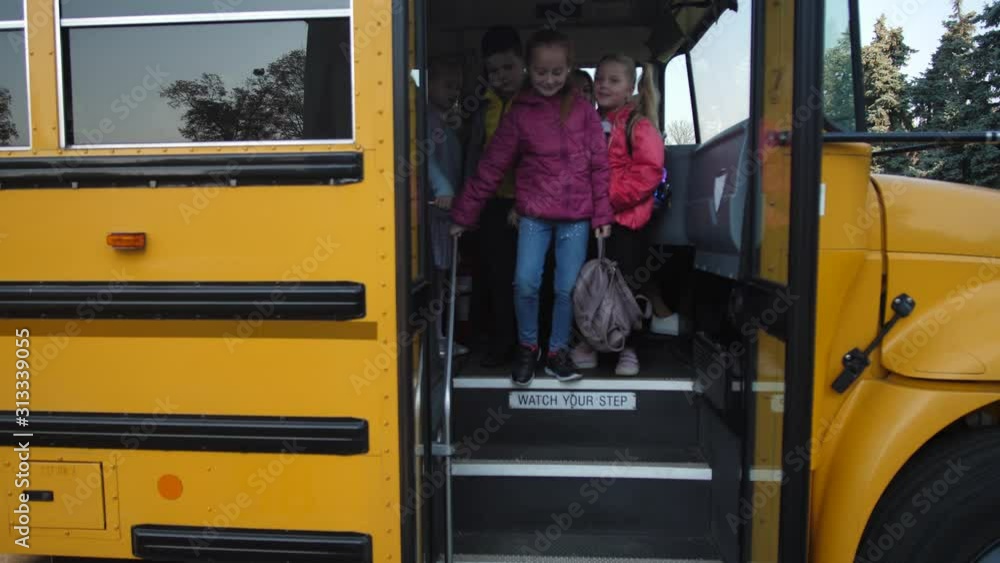 Doors of school bus opening and elementary age schoolchildren going out ...