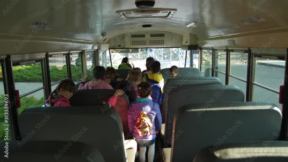 Back view of elementary age schoolchildren rising from seats to get off ...