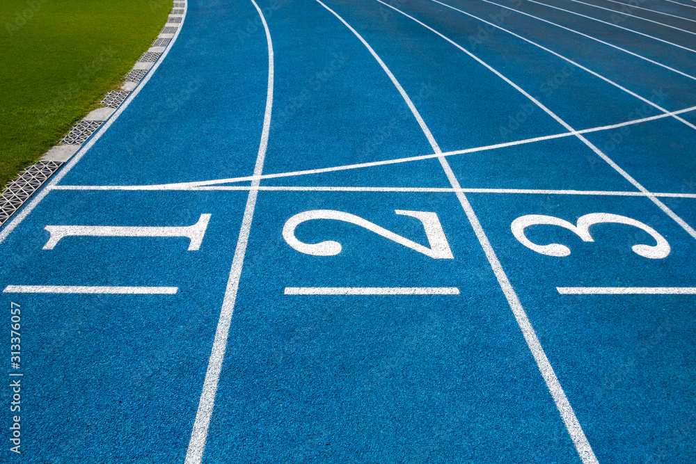 Blue running treadmill track with lane numbers in stadium outdoors ...