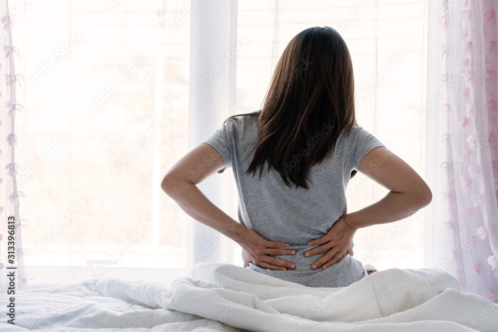 Sad young Asian woman touching back feeling backache morning discomfort ...