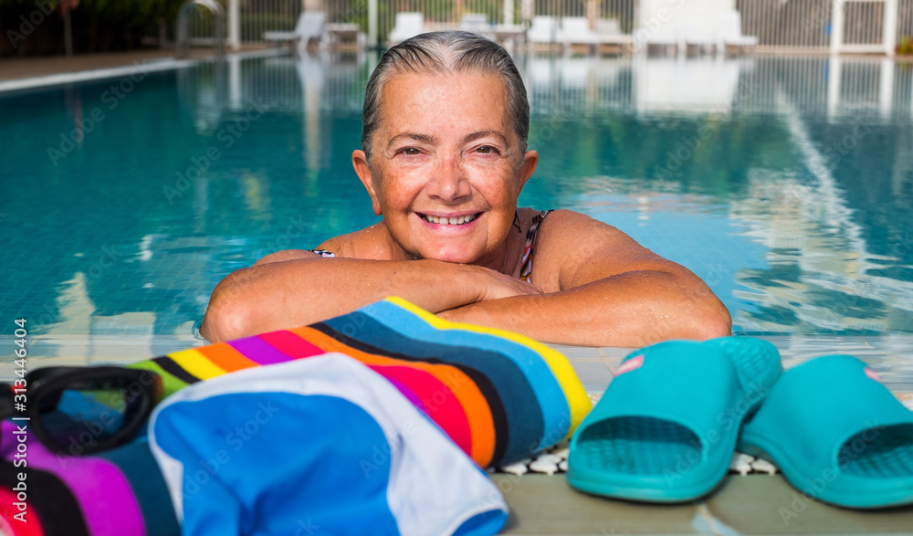 Attractive senior woman enjoys the swimming pool. Outdoor pool with ...