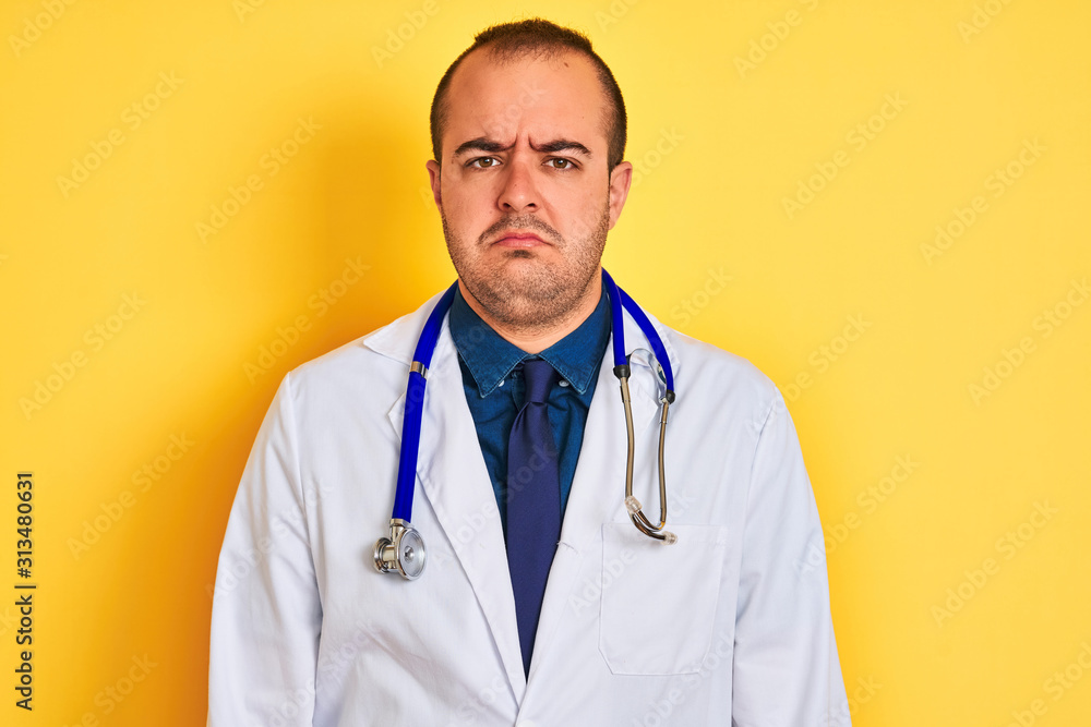 Young doctor man wearing coat and stethoscope standing over isolated ...