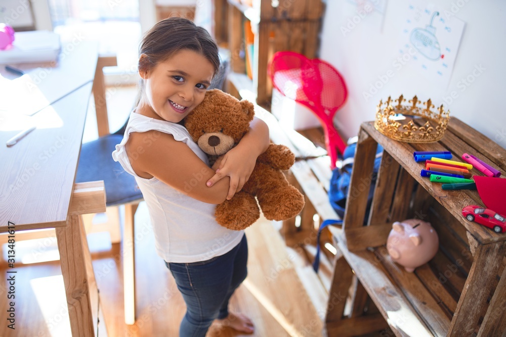 Adorable toddler smiling happy hugging teddy bear around lots of toys ...