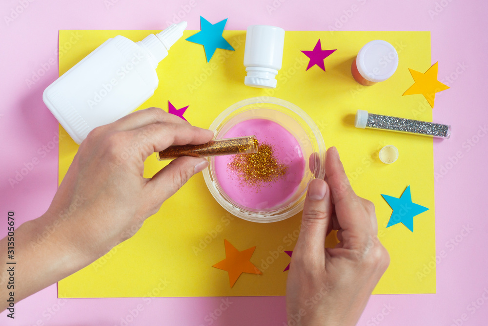 Making slime at home. Girls hands add gold glitter to homemade slime ...