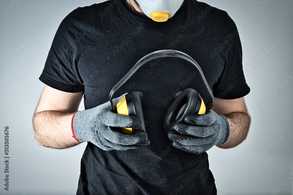 The worker holds ear muffs. Caring for hygiene and safety at work. The ...