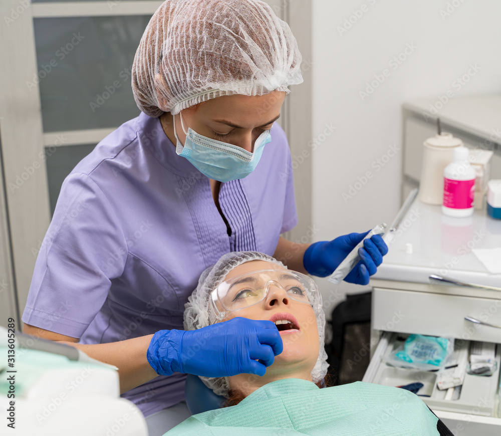 The dentist uses a cotton swab to lubricate the lips of the girl ...