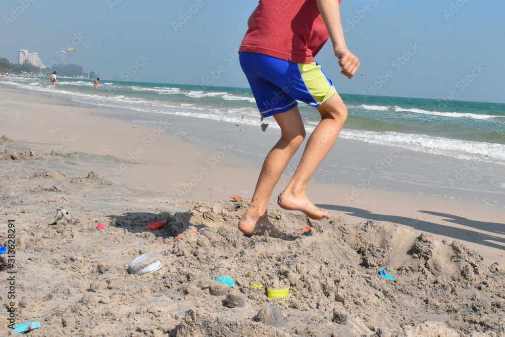 Foto de Trampling feet sand. Little boy breaks a sand castle. The child ...