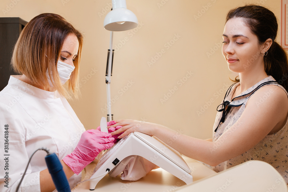 Medicine, cosmetology and manicure. A woman manicure master, in a mask ...