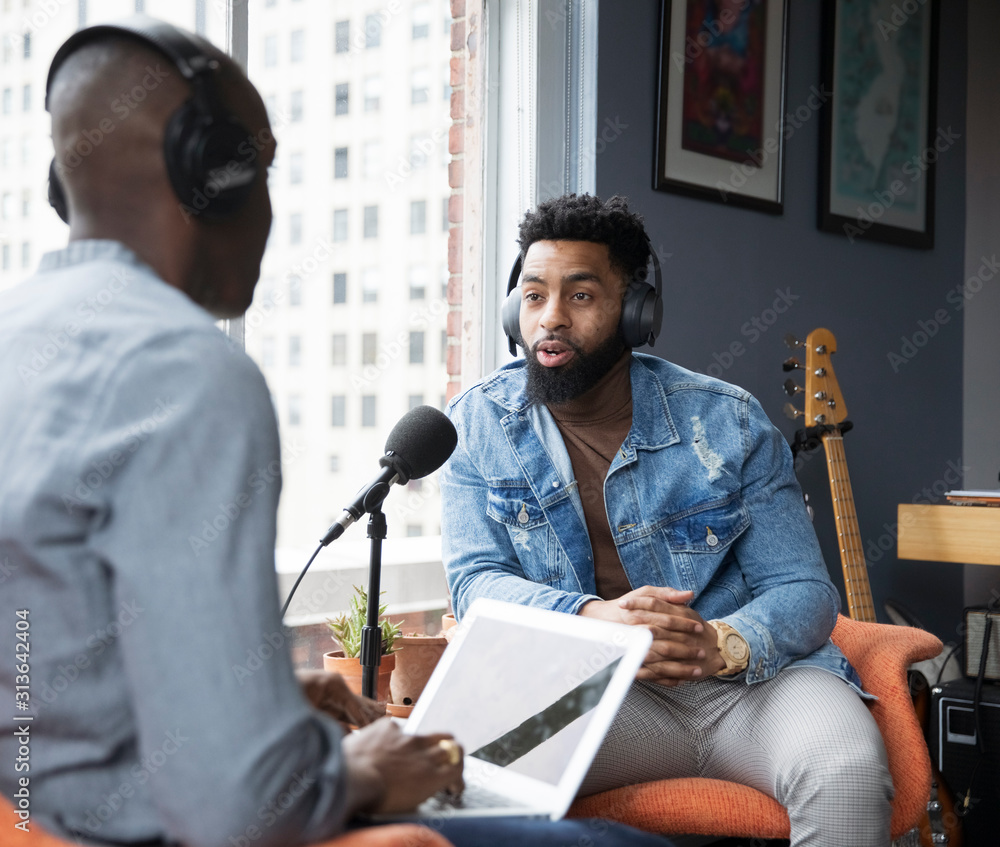 Businessman talking over microphone while sitting with male journalist ...