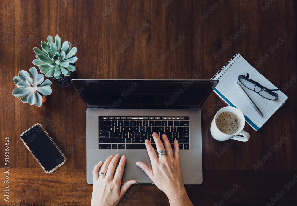 Overhead view of woman's hands working on laptop at wooden table. Stock ...