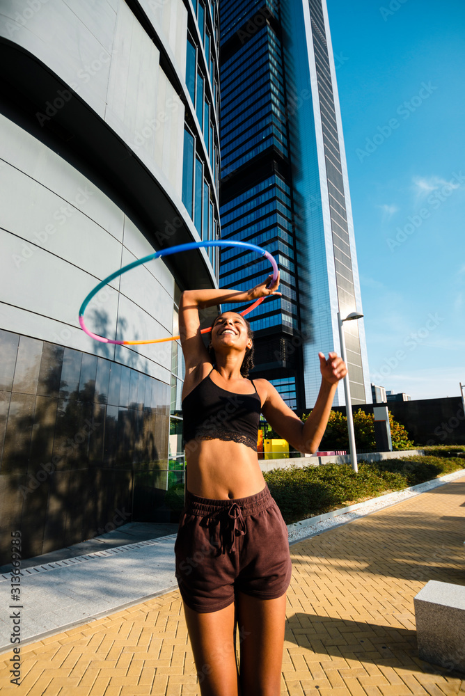 Mixed race generation Z woman performing Hula Hoop dance in downtown ...