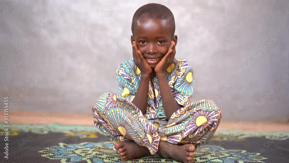 Smiling Little African Boy Sitting Legs Crossed On A Mat With His Head ...