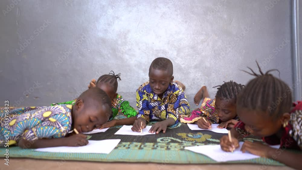 Four Smart Little African Children Lying on The Floor Writing On A ...