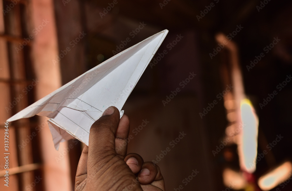 closeup of the hand of a child about to throw a paper plane made with a ...