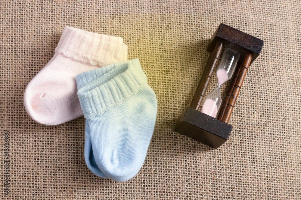 Gender reveal. Boy or girl? Pink or blue. With sand clock ticking as ...