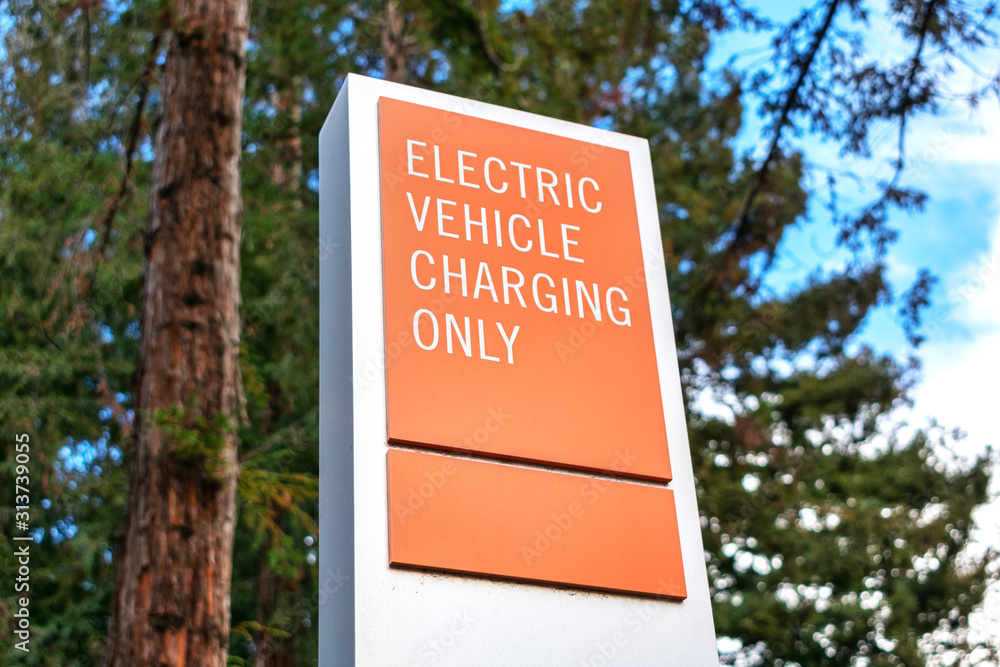 Electric vehicle charging only warning sign with blurred green trees in ...