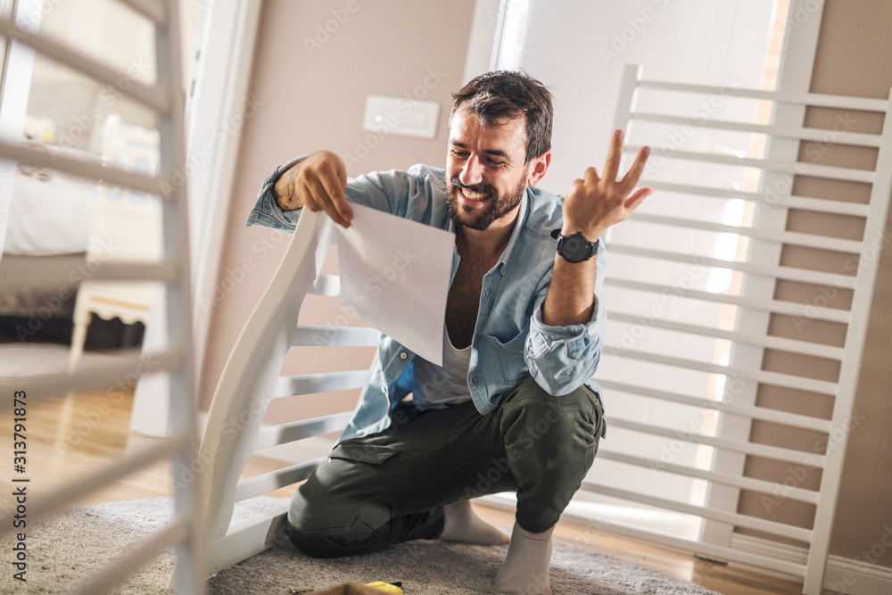 Man trying to understand instructions for installation of a baby crib ...