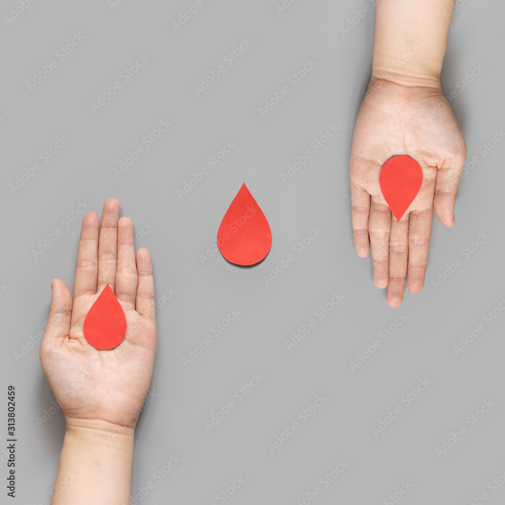 Blood donation - Human hand giving blood drop symbol to a hand on gray ...