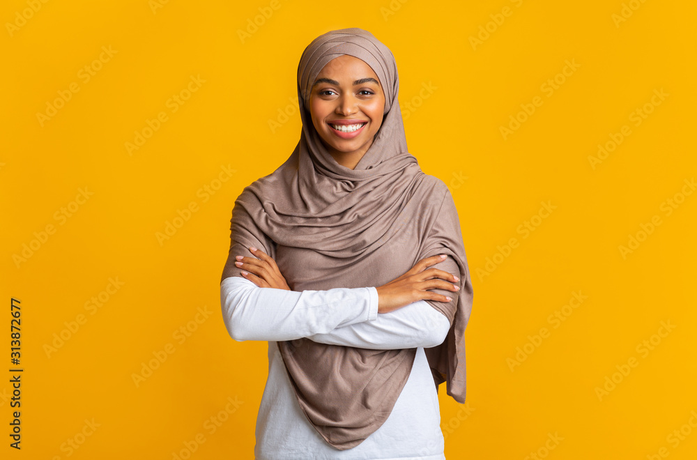 Portrait of black muslim girl in hijab over yellow studio background ...