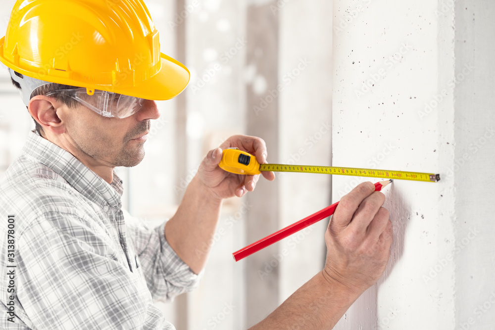 Builder marking measurements on a white wall Stock Photo | Adobe Stock