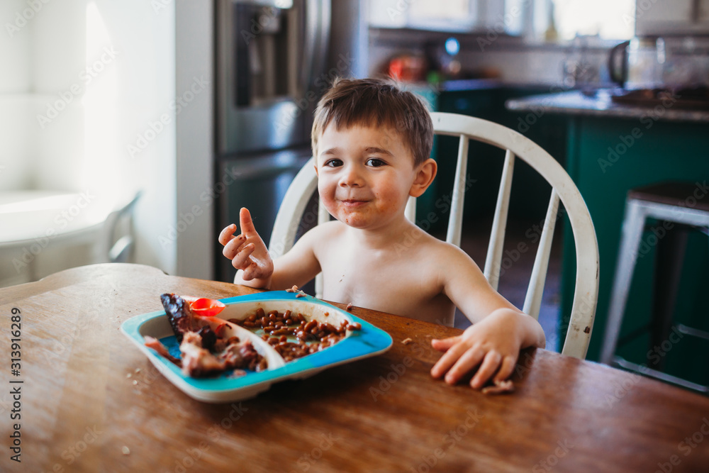 Young boy smiling with eating lunch at dining table Stock Photo | Adobe ...